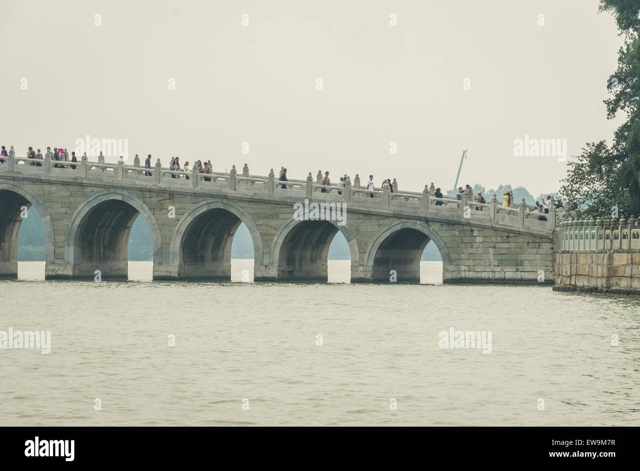People walking over arched stone bridge Stock Photo - Alamy