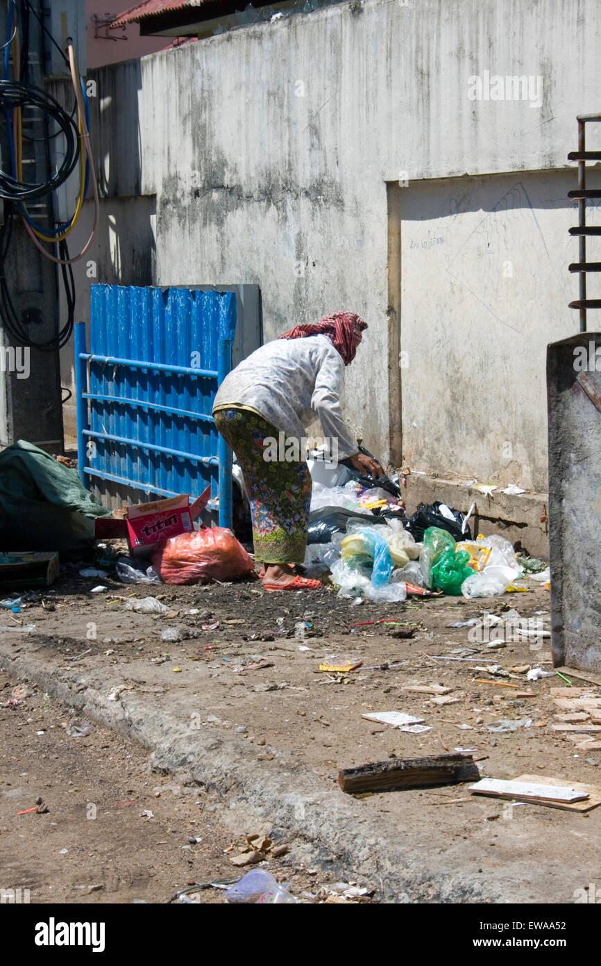 An elderly woman is scavenging through plastic for recyclable material ...