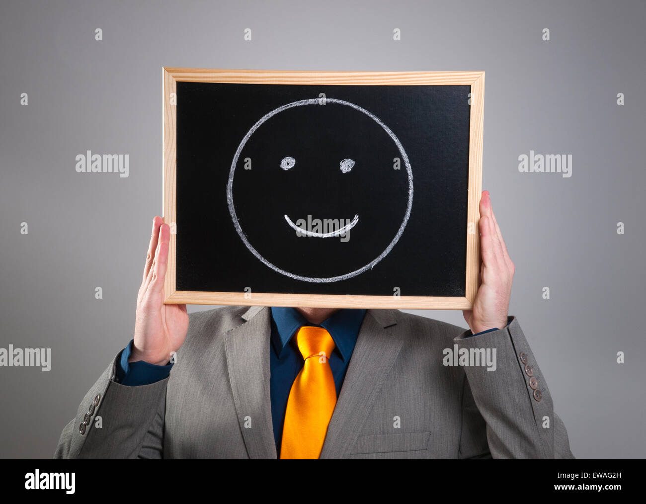 Businessman hiding his face with a white billboard with a smiley face ...