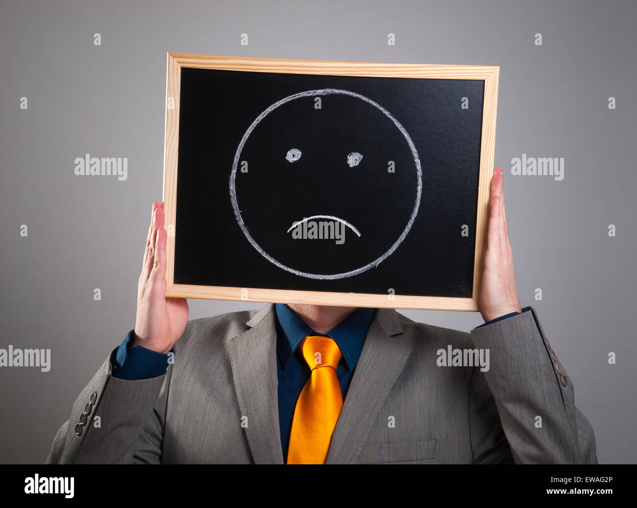 Businessman hiding his face with a white billboard with a sad face on ...