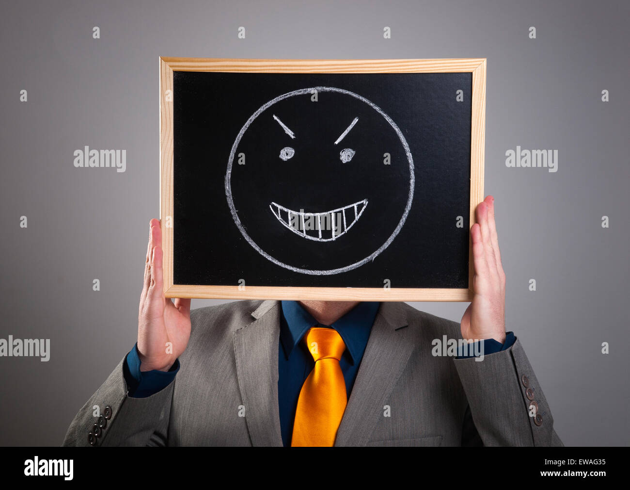 Businessman hiding his face with a white billboard with a evil face on ...