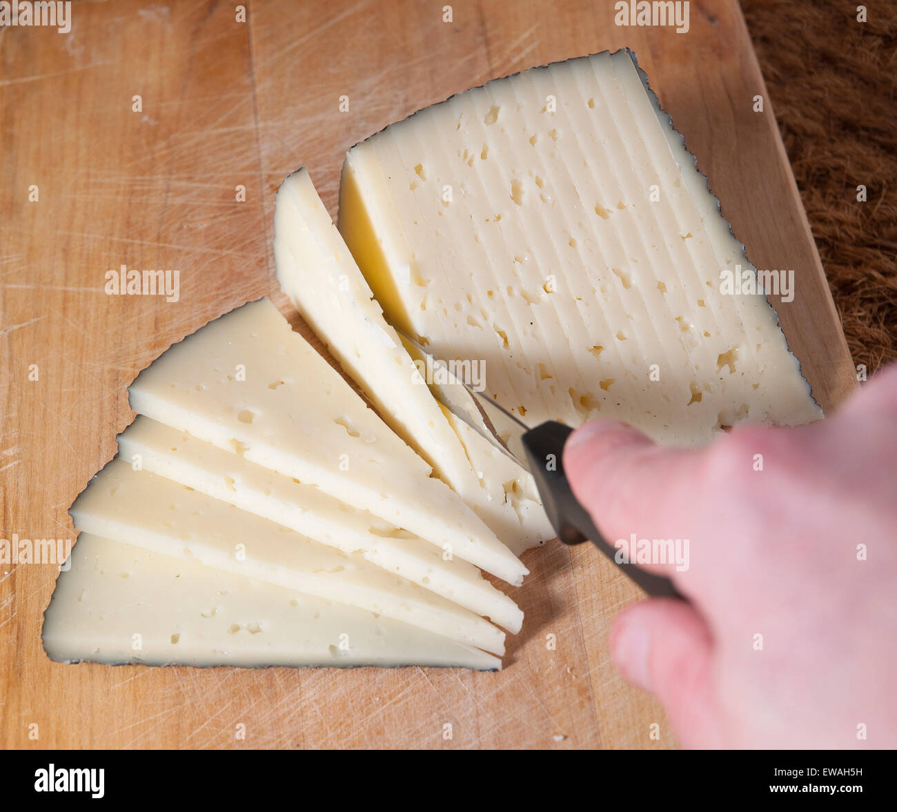 Man cutting a piece of Spanish cheese on a wooden board Stock Photo - Alamy