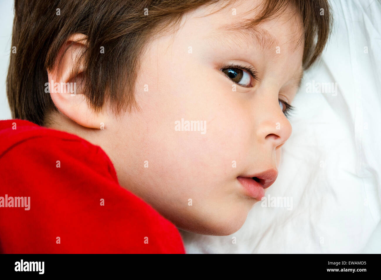 Close up head shot of young child, boy, 4 year old, laying down with ...