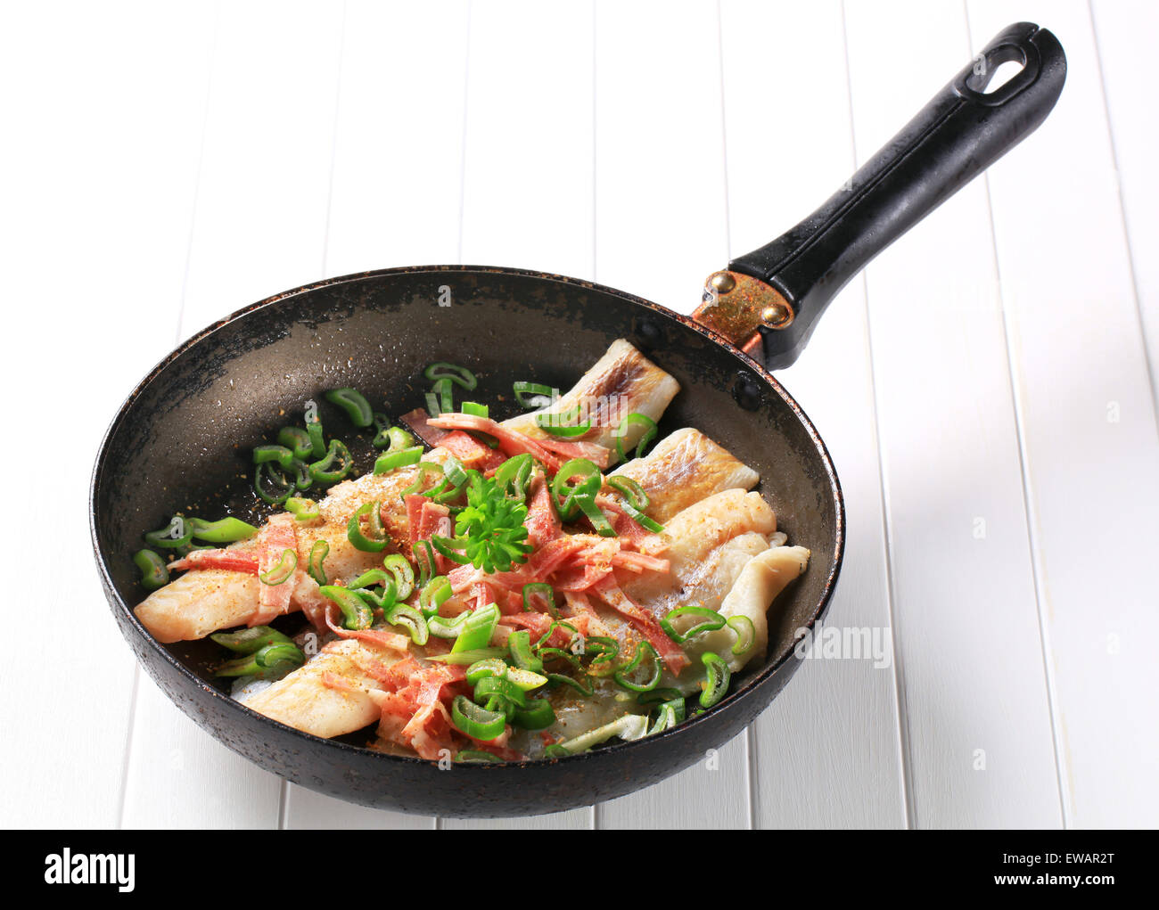 Pan fried fish fillets with bacon and spring onion Stock Photo - Alamy