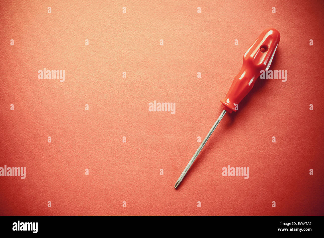 Just one red used screwdriver, simple composition on red background ...