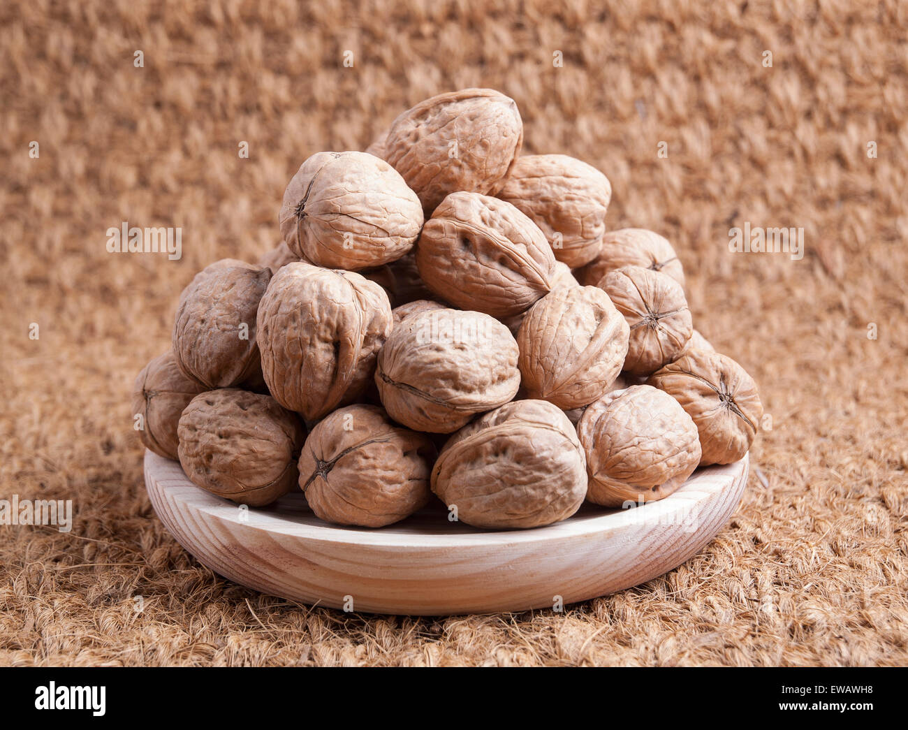 Walnuts on a wooden plate and on a straw background Stock Photo - Alamy