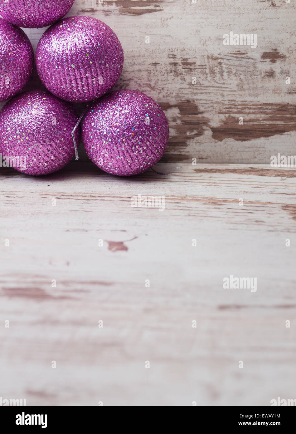Pink christmas balls in a stack over wooden background in a studio shot ...