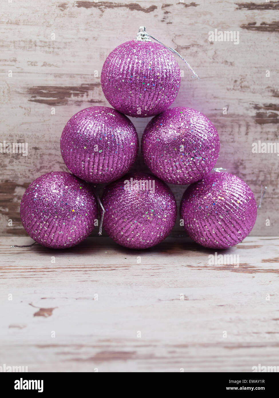 Pink christmas balls in a stack over wooden background in a studio shot ...