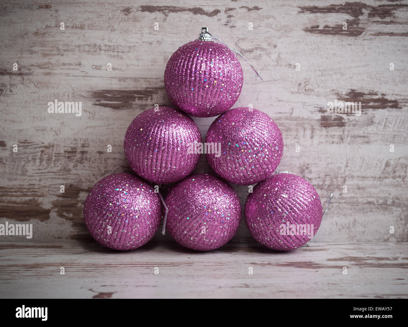 Pink christmas balls in a stack over wooden background in a studio shot ...