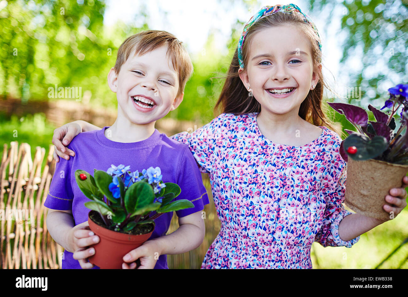 Joyful kids with garden violets looking at camera Stock Photo - Alamy
