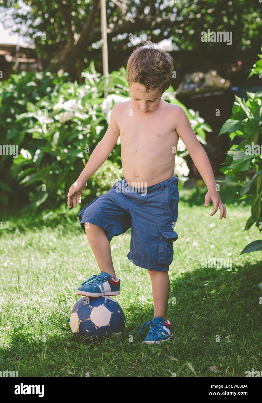 Blond boy stepping on a ball in a summer day Stock Photo - Alamy