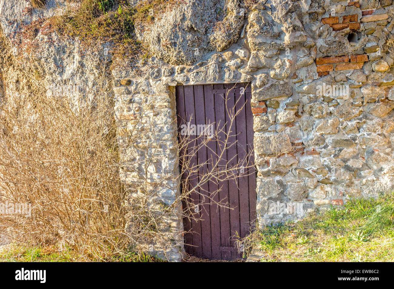 wooden square door of an ancient fortress with white stone walls in ...