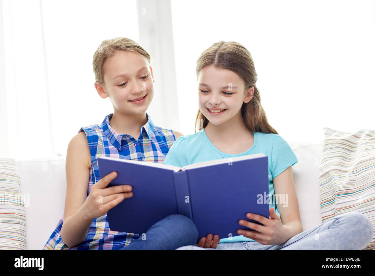 two happy girls reading book at home Stock Photo - Alamy