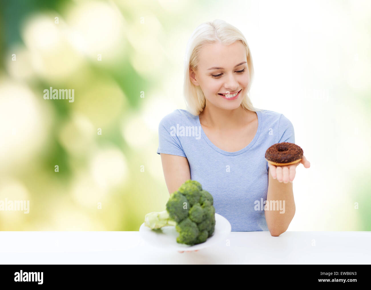 smiling woman with broccoli and donut Stock Photo - Alamy