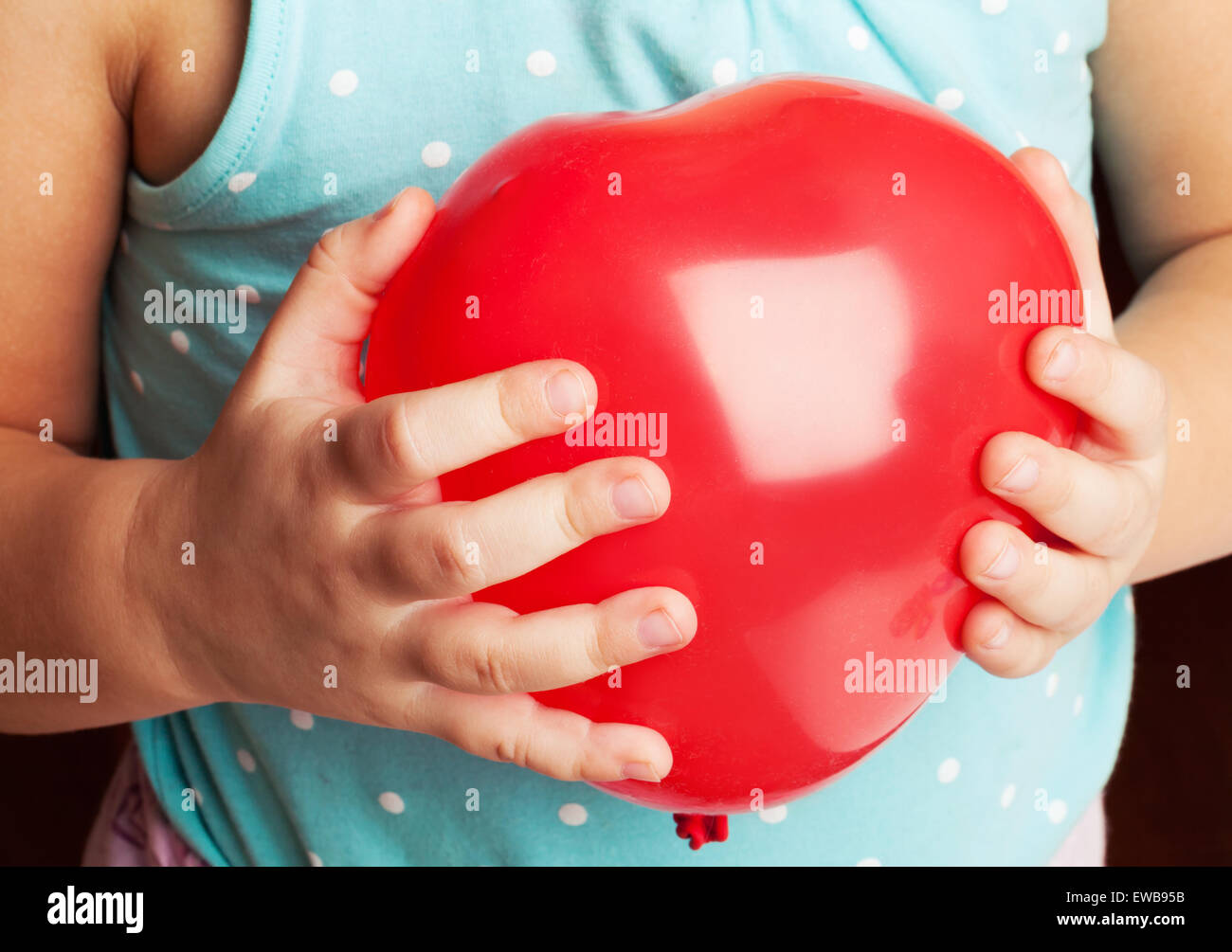 Caucasian baby girl holds red heart shaped balloon in her hands Stock ...