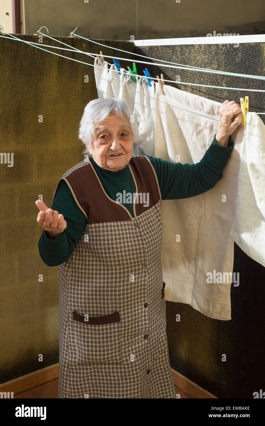 Elderly woman hanging out the washing on the terrace of her house Stock ...