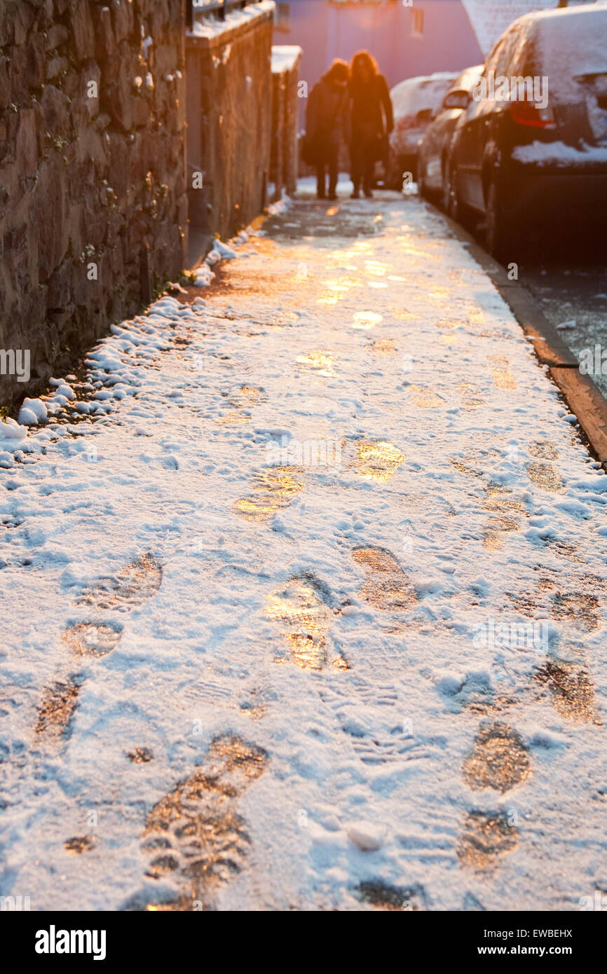Snowy pavement with footprints and p[eople walking up hill Stock Photo ...