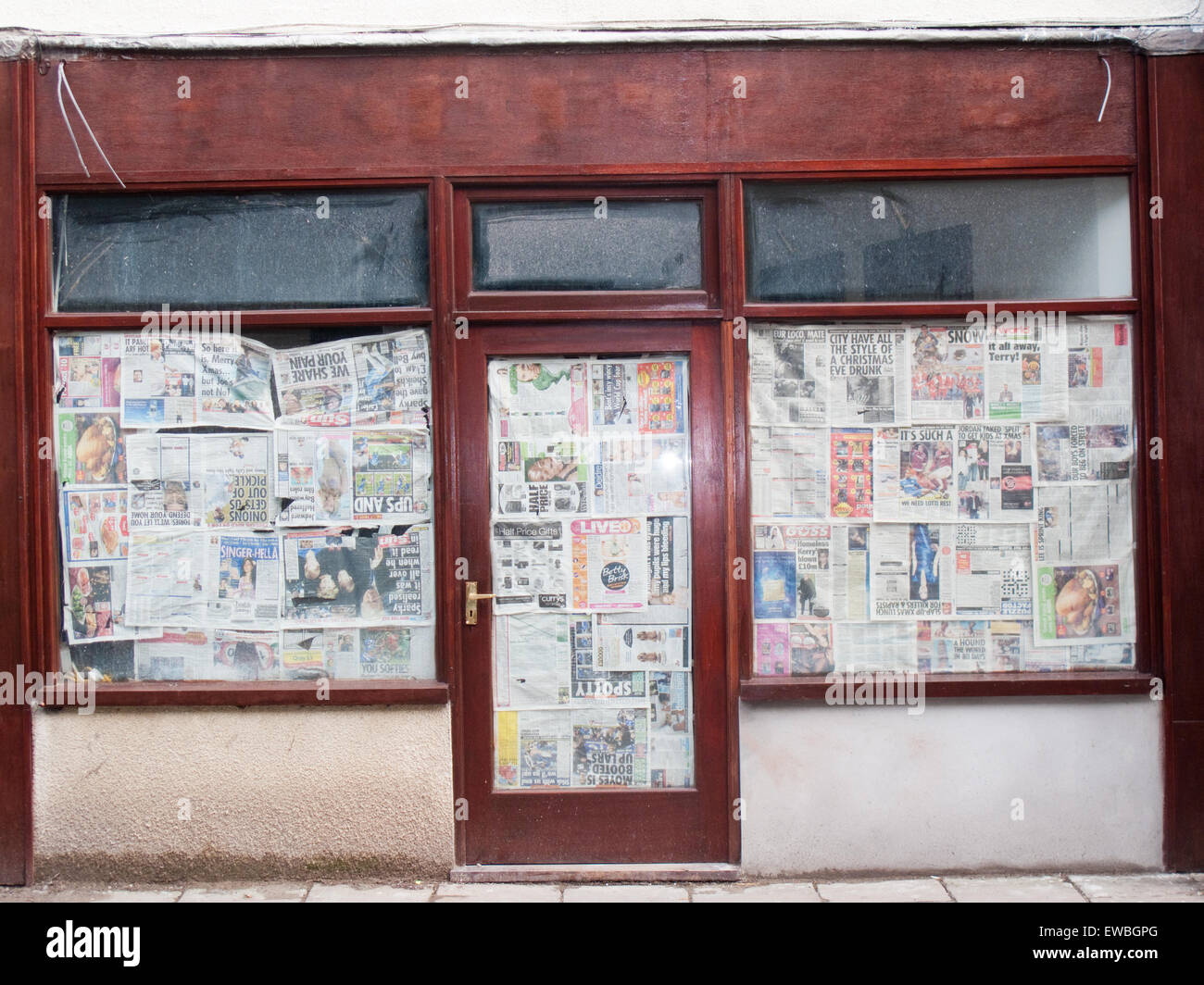 Disused shop front with newspapers covering windows Stock Photo - Alamy