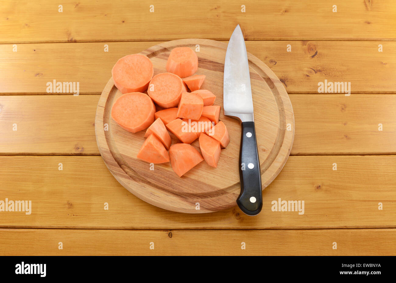 Pieces of chopped sweet potato with a sharp kitchen knife on a wooden ...