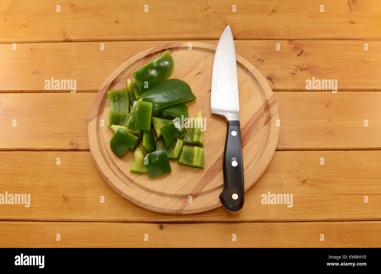 Raw green pepper being cut into pieces with a sharp kitchen knife on a ...