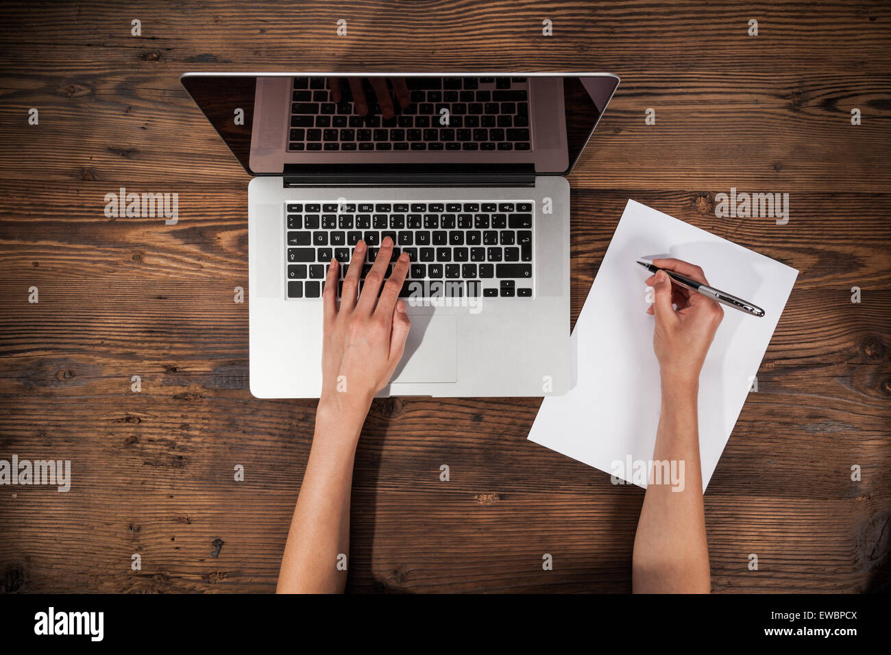 Aerial view of woman typing on laptop. Placed on wooden desk Stock ...
