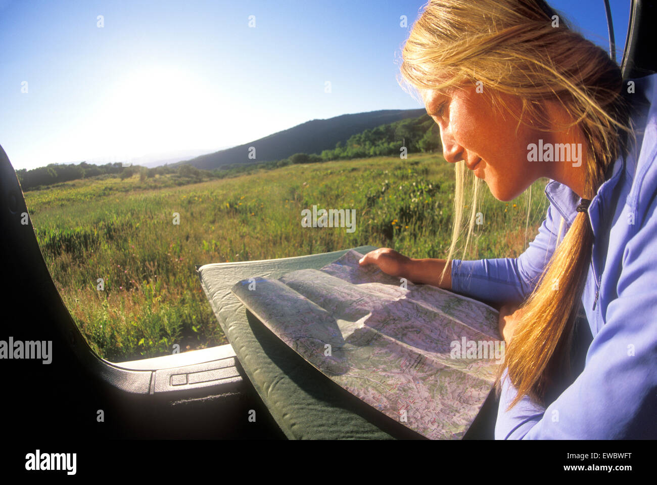 Woman reading a map while car camping, Colorado Stock Photo - Alamy