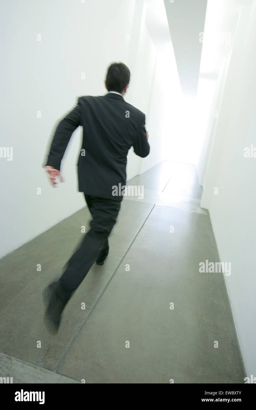 A man running down a long hallway toward a bright light Stock Photo - Alamy