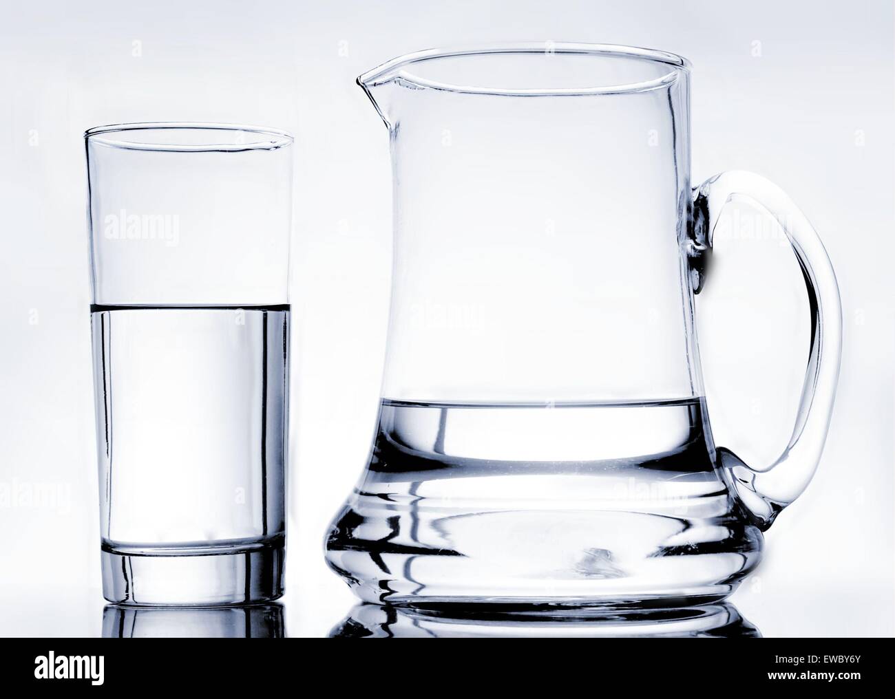 A pitcher and a glass partially filled with clear, clean, pure water ...