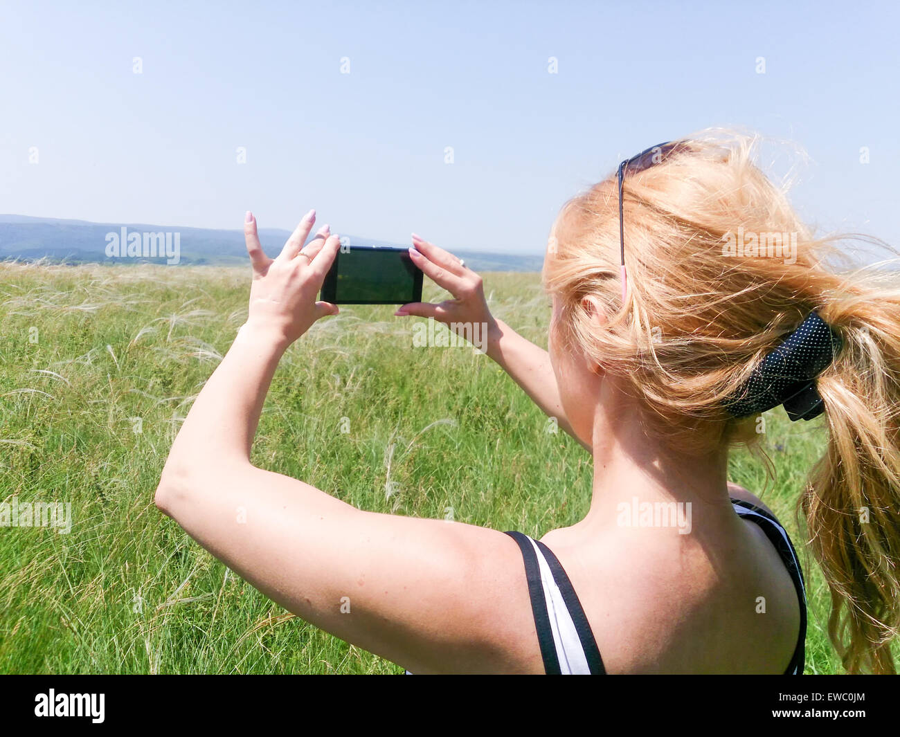 Young female photographer taking pictures outdoors. Woman with mobile ...