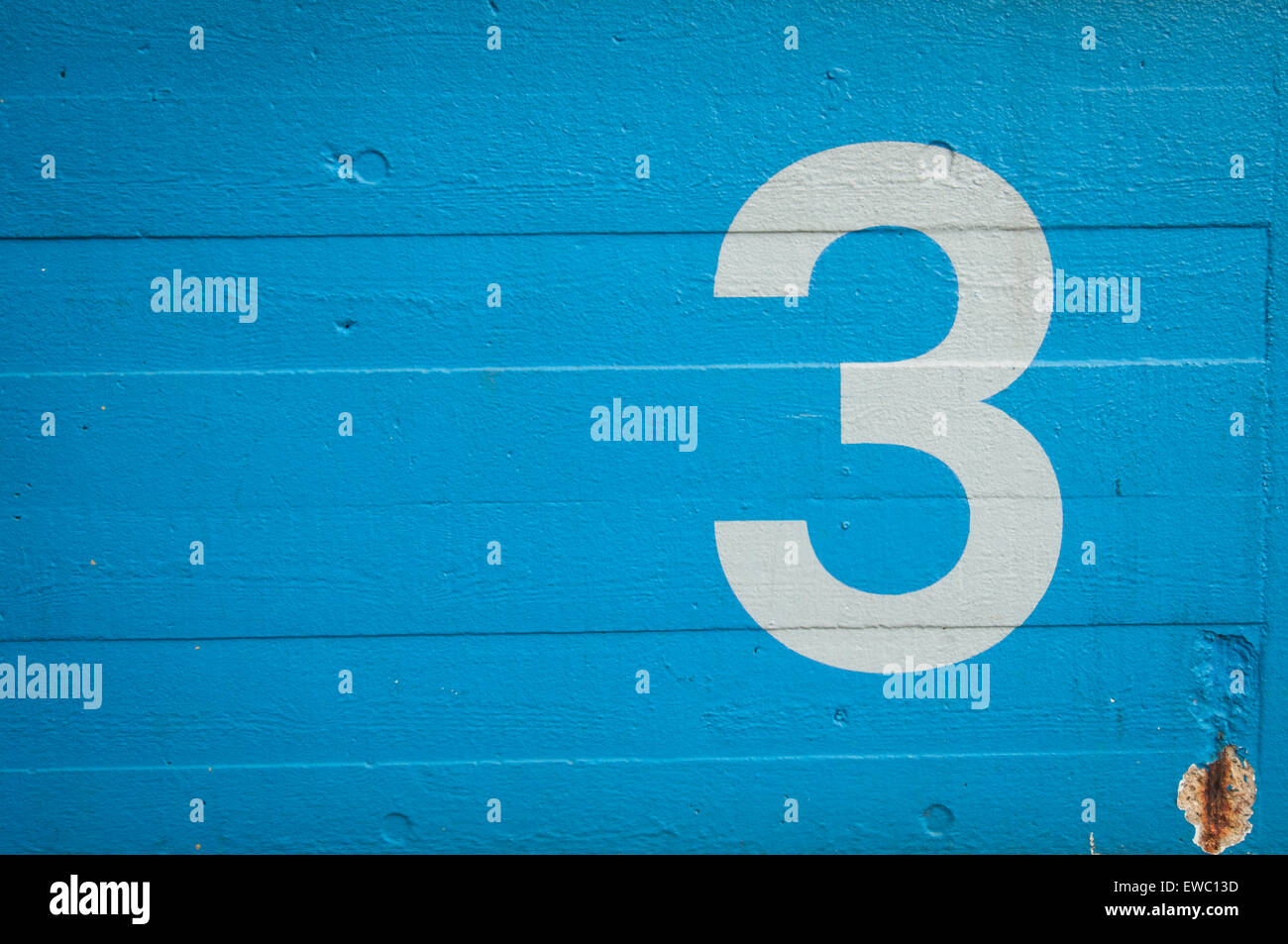 The number 3 painted on a blue concrete wall Stock Photo - Alamy