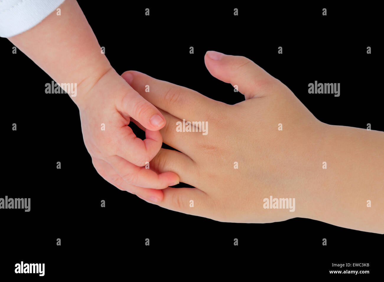 Hand of newborn baby touching hand of child isolated on black ...