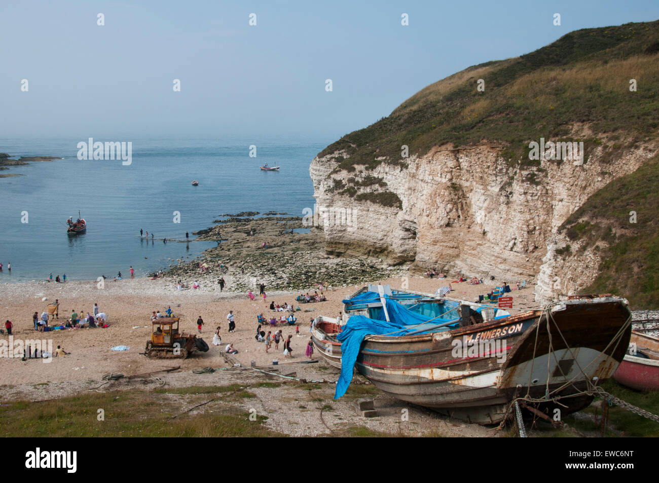 Old wooden fishing boat, chalk cliffs, people on the sunny summer sand ...