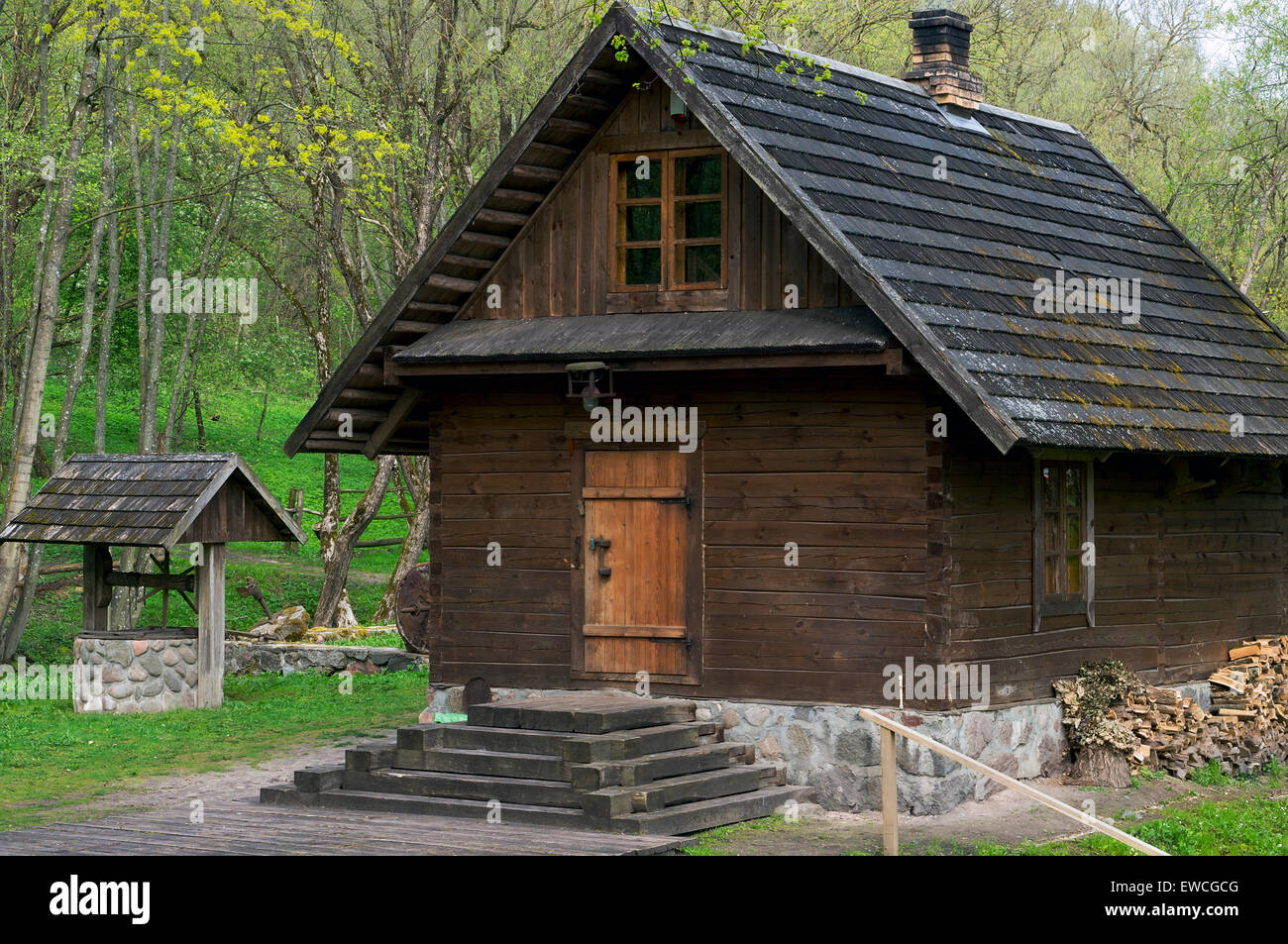 Wooden simple mass production shed near a well. Spring forest and green ...