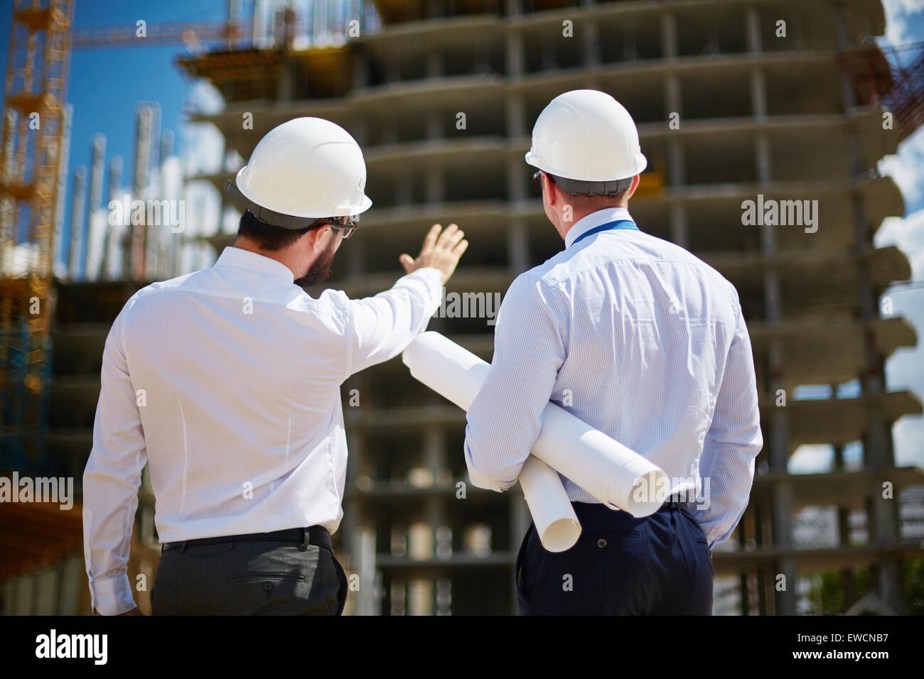 Rear view of architects looking at construction Stock Photo - Alamy