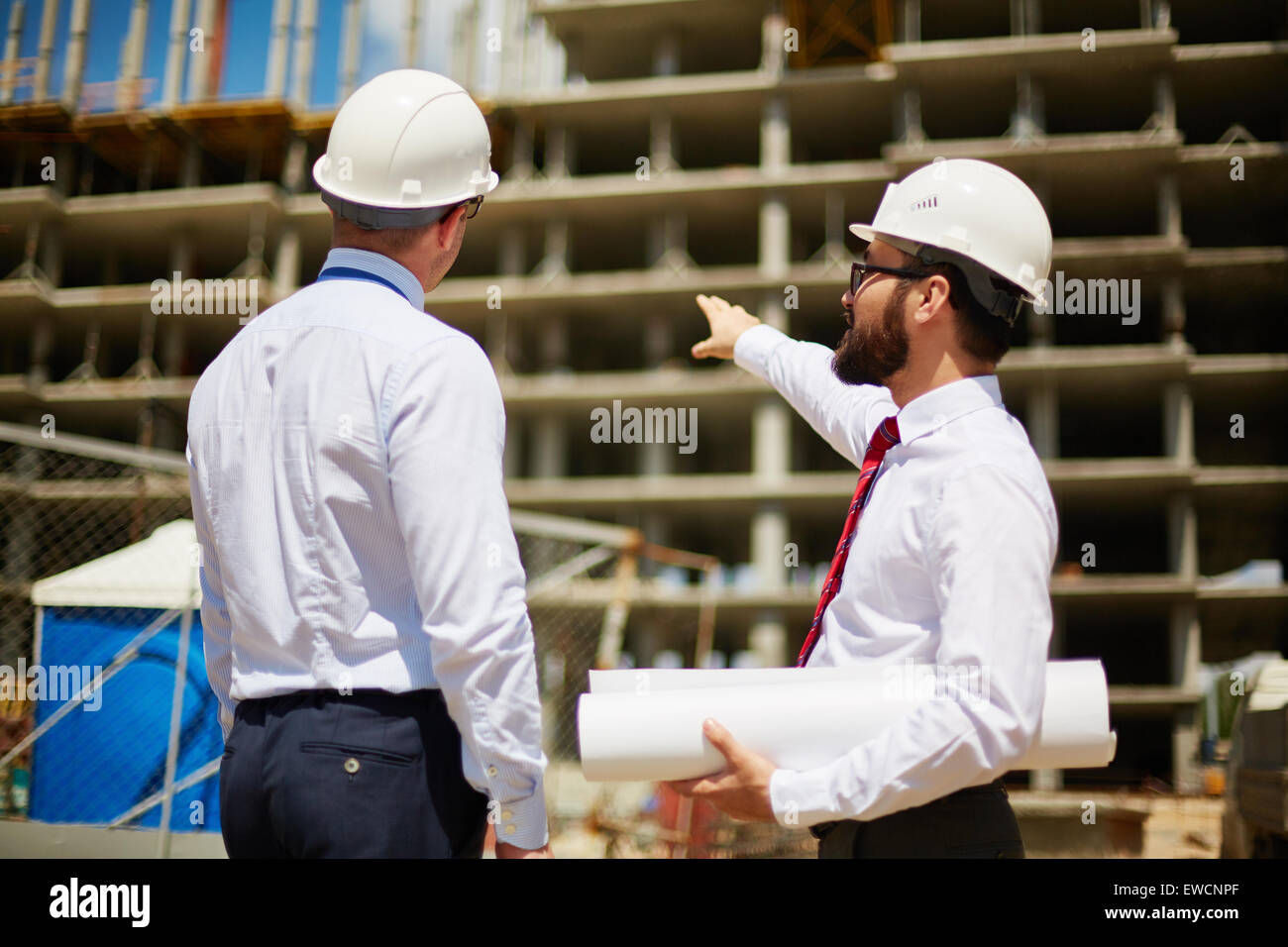 Young architects looking at construction and discussing its details ...