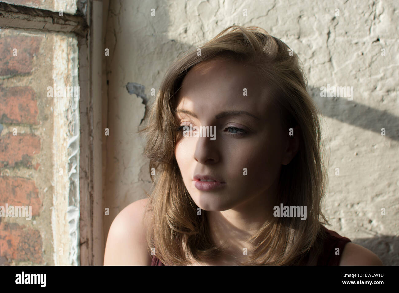 Beautiful young pensive woman looking out of the window Stock Photo - Alamy