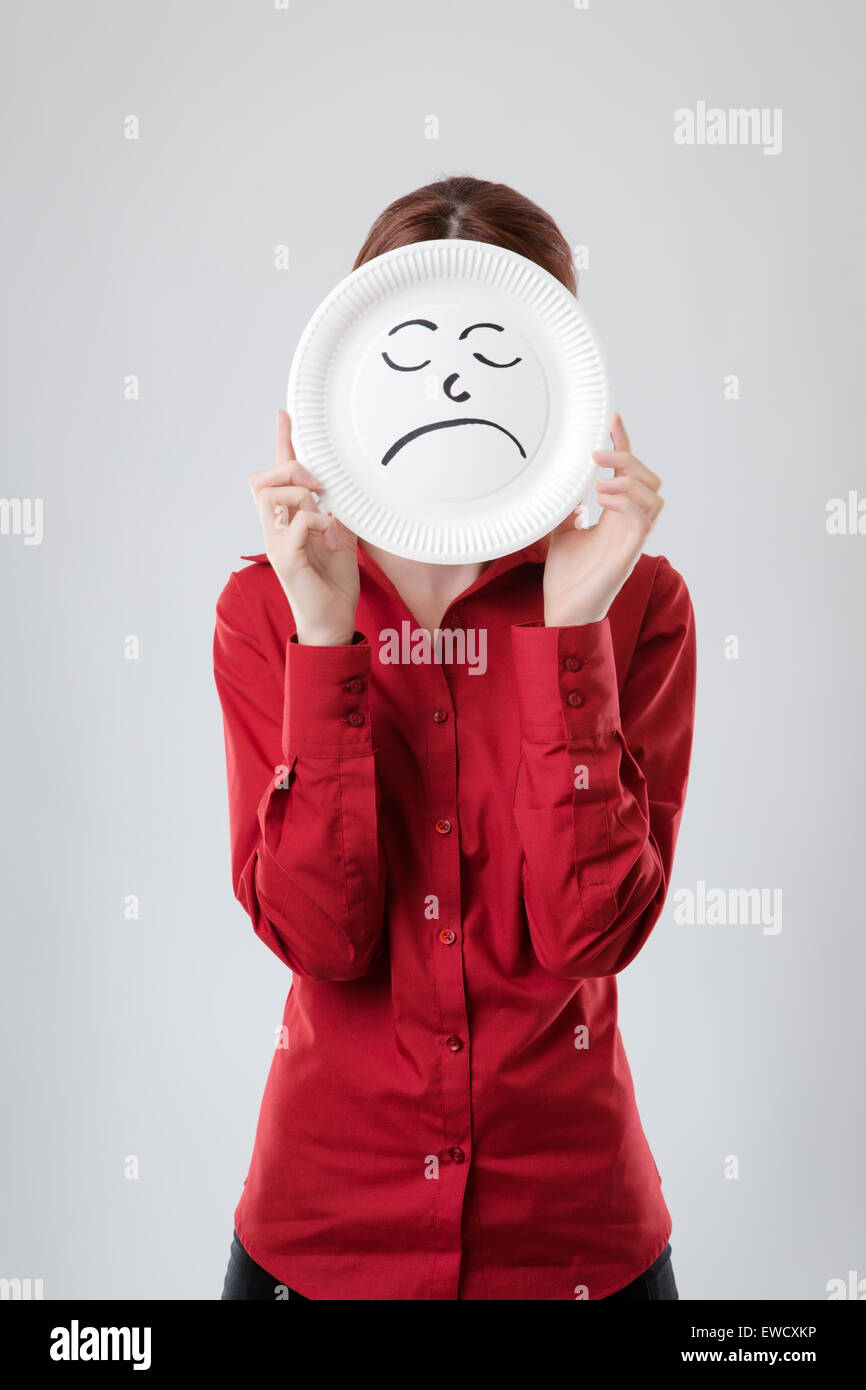 business woman holding a paper plate up to her face with a unhappy face ...