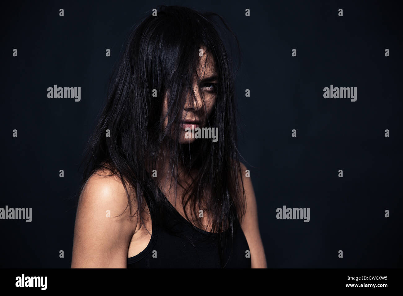 Portrait of exhausted woman looking at camera over black background ...