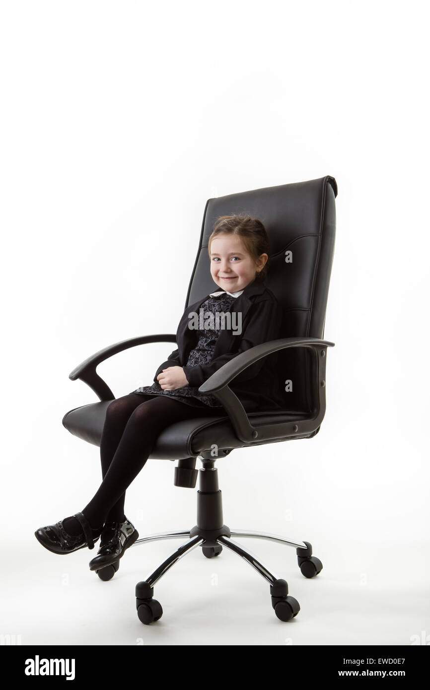 young girl siting in a office chair writing something in a note book ...