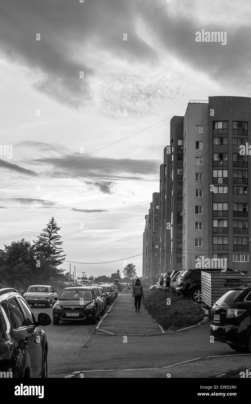 Woman walking in a city with high rise and clouds Stock Photo - Alamy