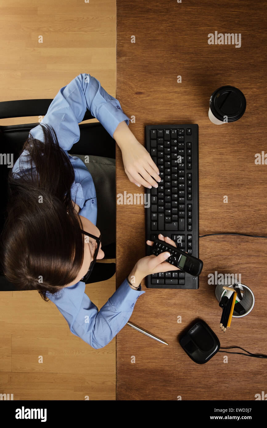woman at her desk on the phone working taken from a birds eye view ...