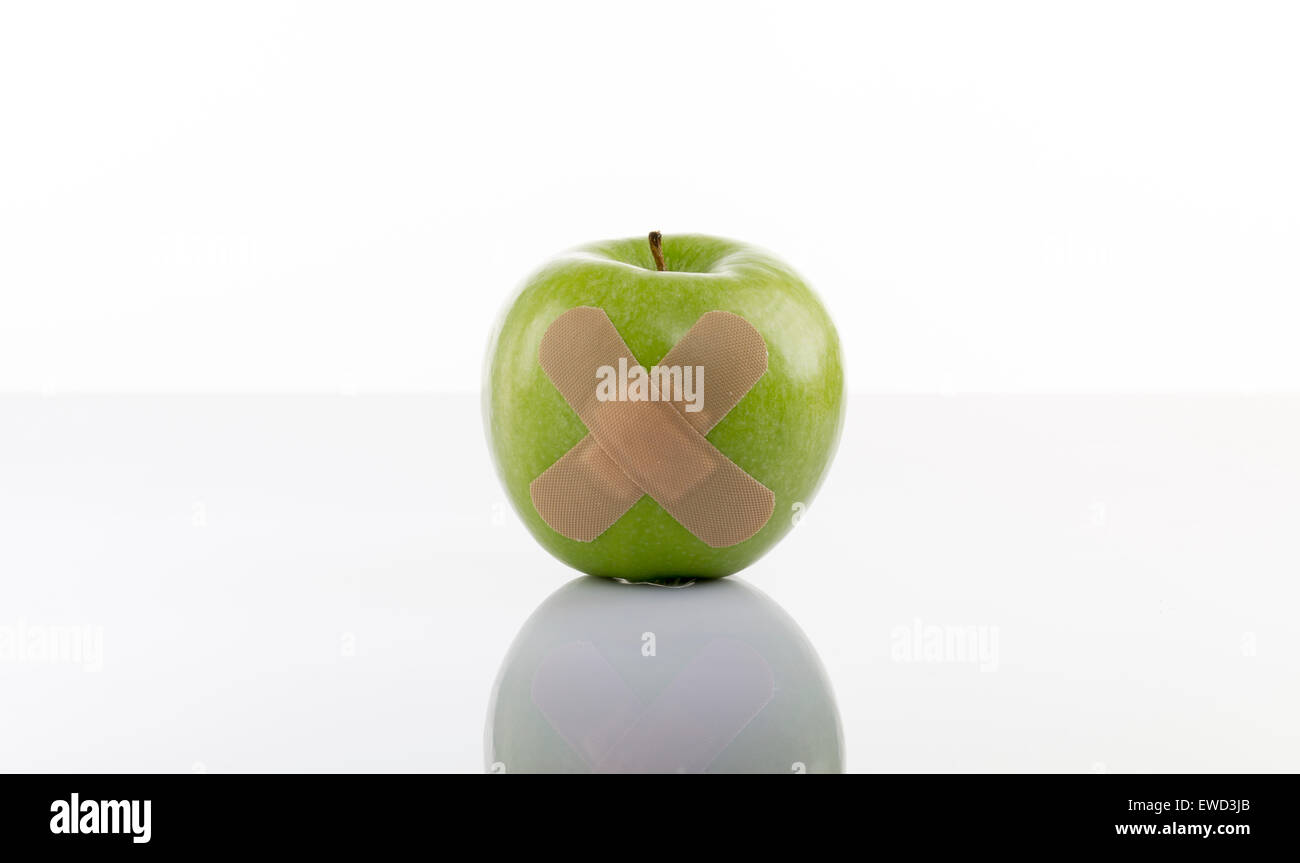 A Green apple with a band-aid on white background Stock Photo - Alamy
