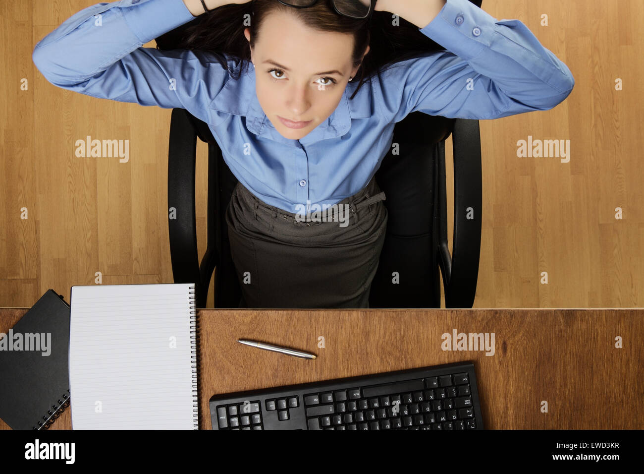 woman relaxing at her desk looking up at camera taken from a birds eye ...