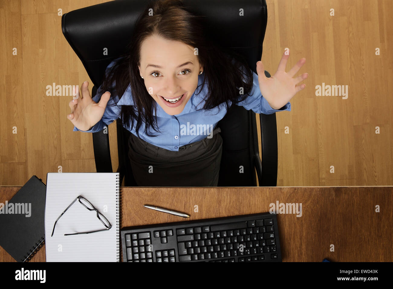 woman at her desk looking up very happy and excited, taken from a birds ...