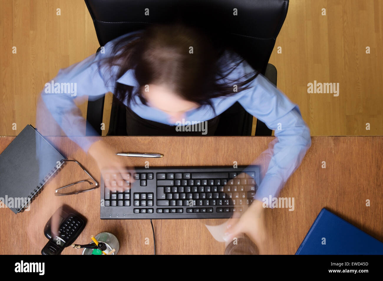 woman typing and working hard at her desk taken from a birds eye view ...
