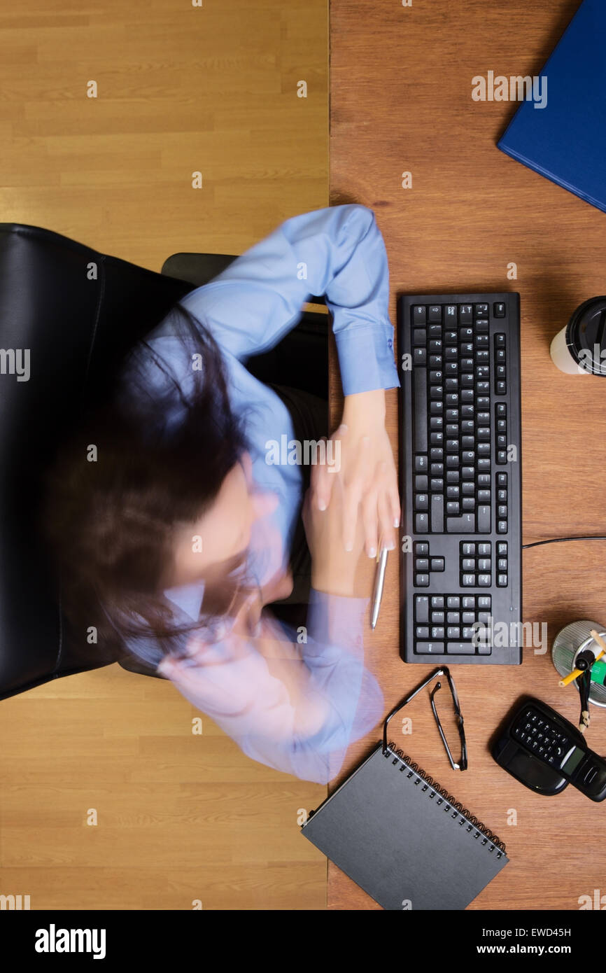 woman typing and working hard at her desk taken from a birds eye view ...
