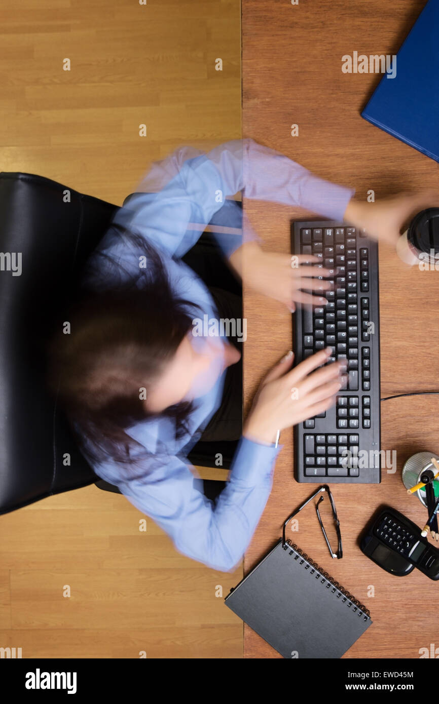 woman typing and working hard at her desk taken from a birds eye view ...