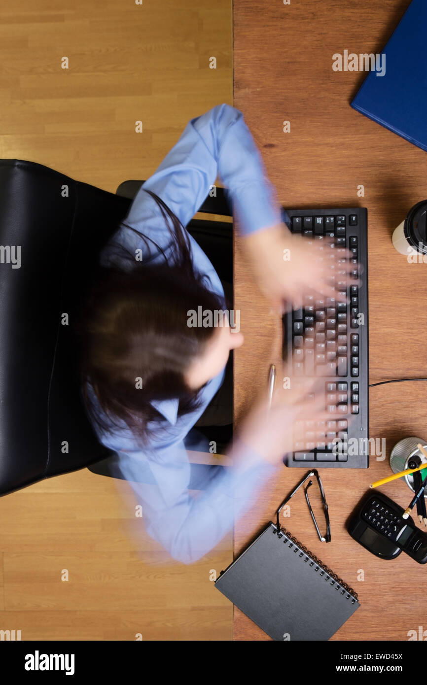 woman typing and working hard at her desk taken from a birds eye view ...