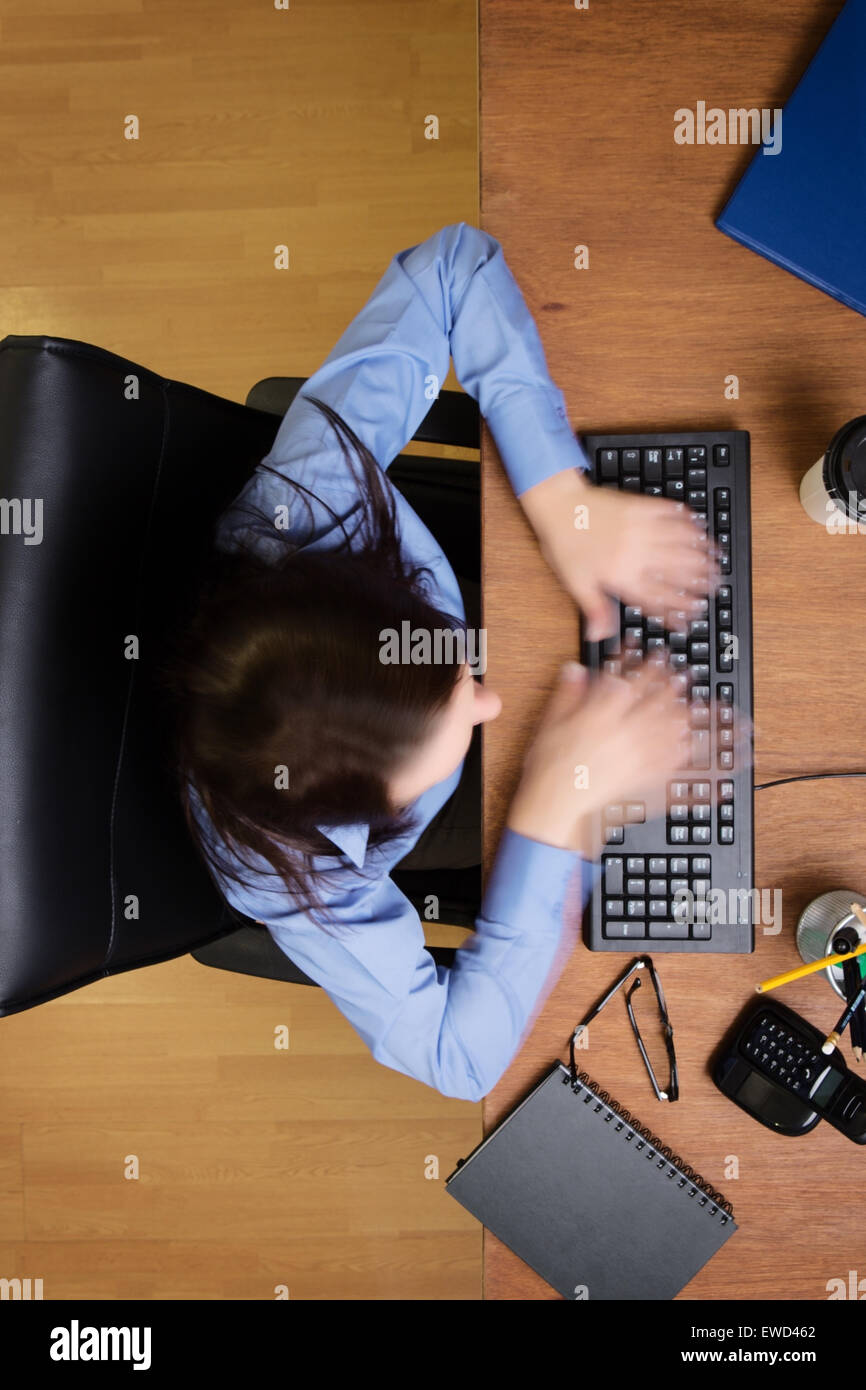 woman typing and working hard at her desk taken from a birds eye view ...