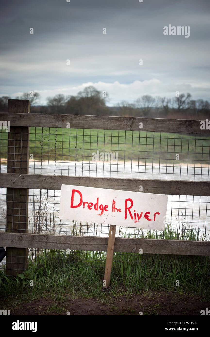 A 'Dredge the River' sign next to a pump outlet draining the flooded ...